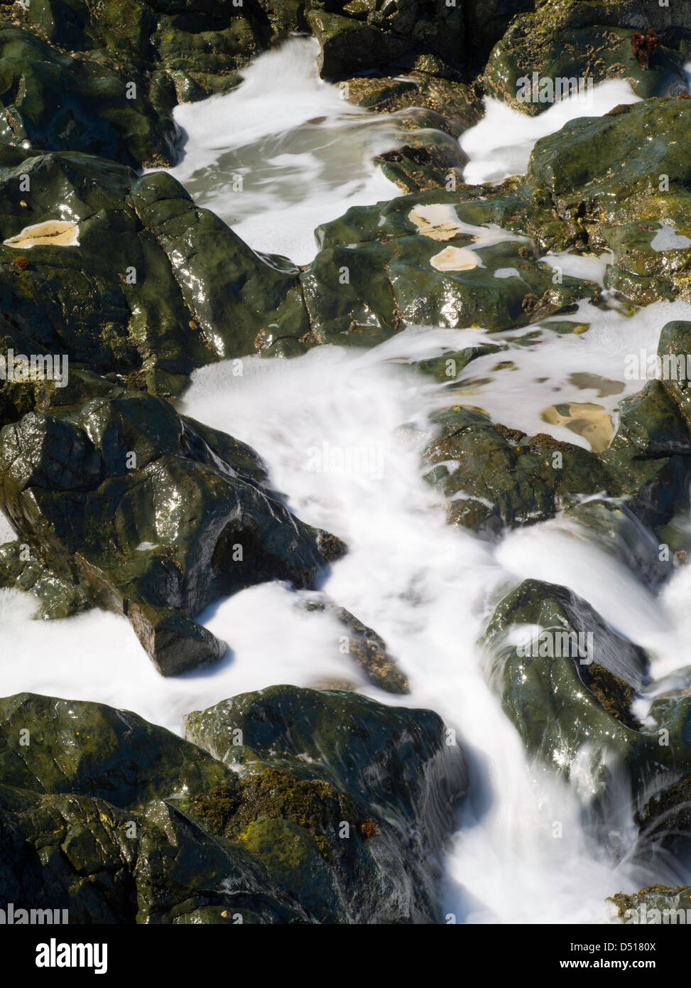 Waves crash on sea-side rocks, slowly carving the rock and creating ...
