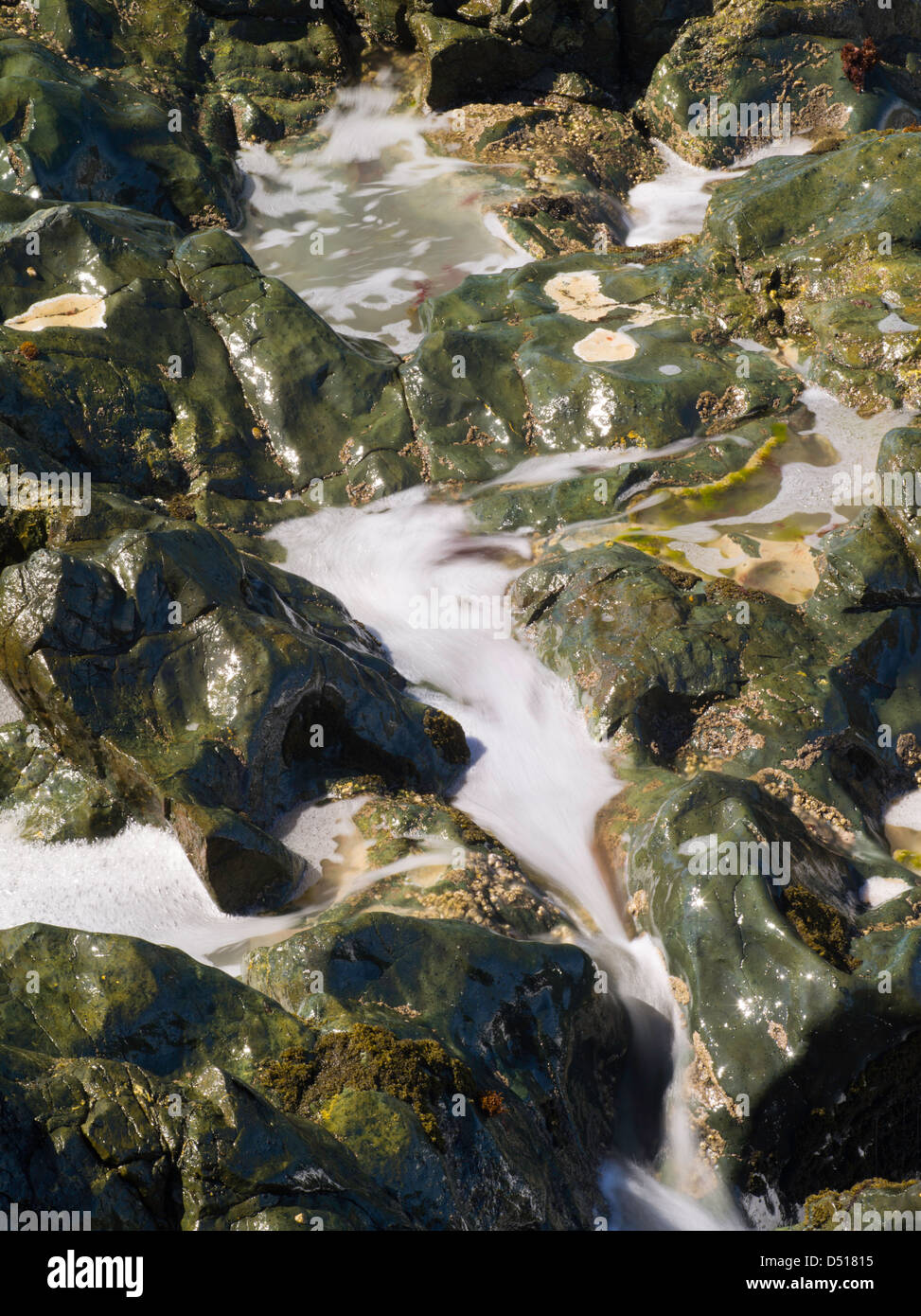 Waves crash on sea-side rocks, slowly carving the rock and creating ...