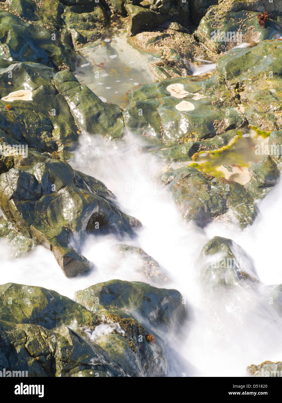 Waves crash on sea-side rocks, slowly carving the rock and creating ...