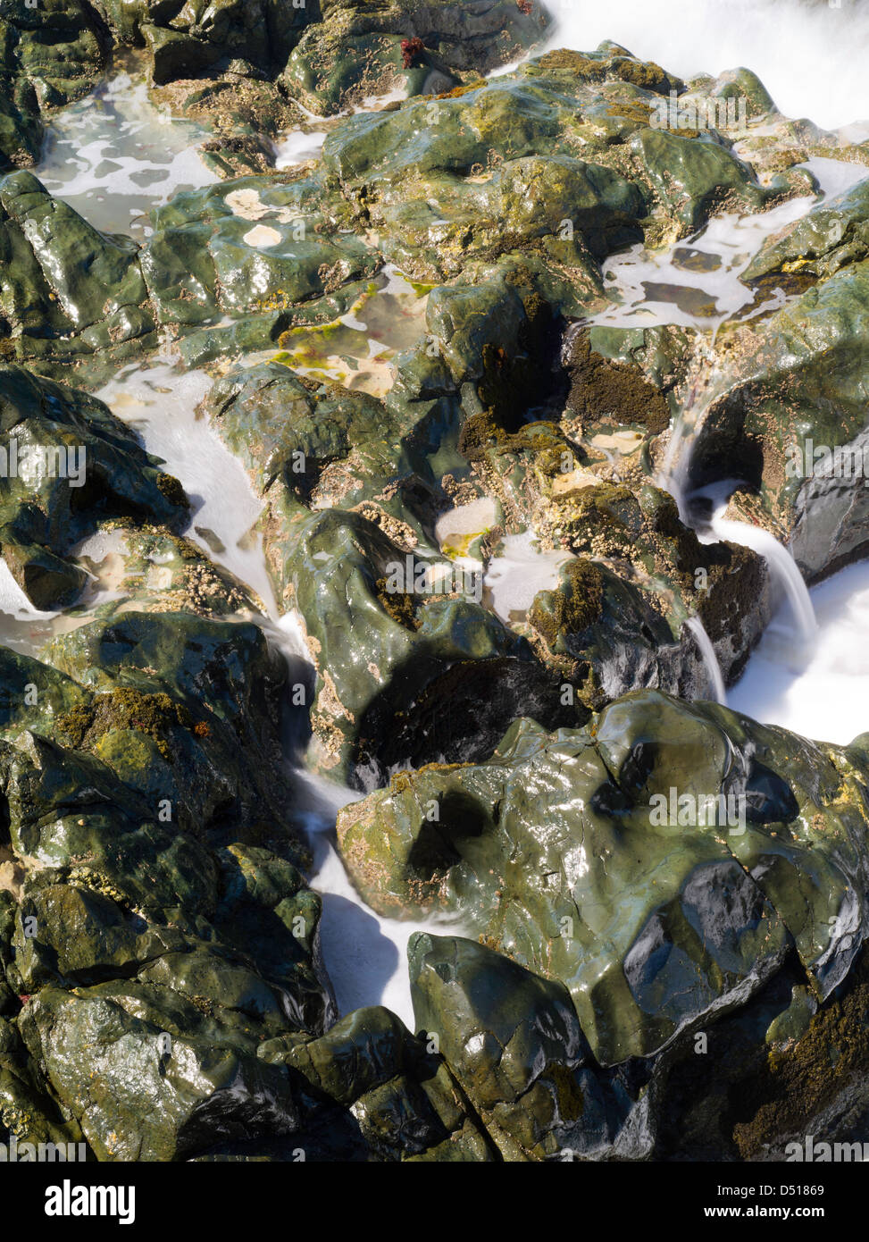 Waves crash on sea-side rocks, slowly carving the rock and creating ...