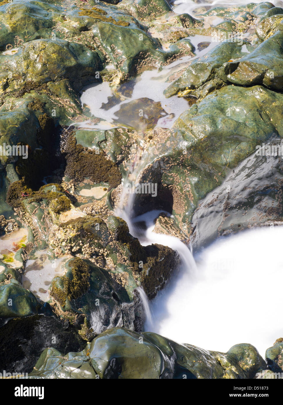 Waves crash on sea-side rocks, slowly carving the rock and creating ...