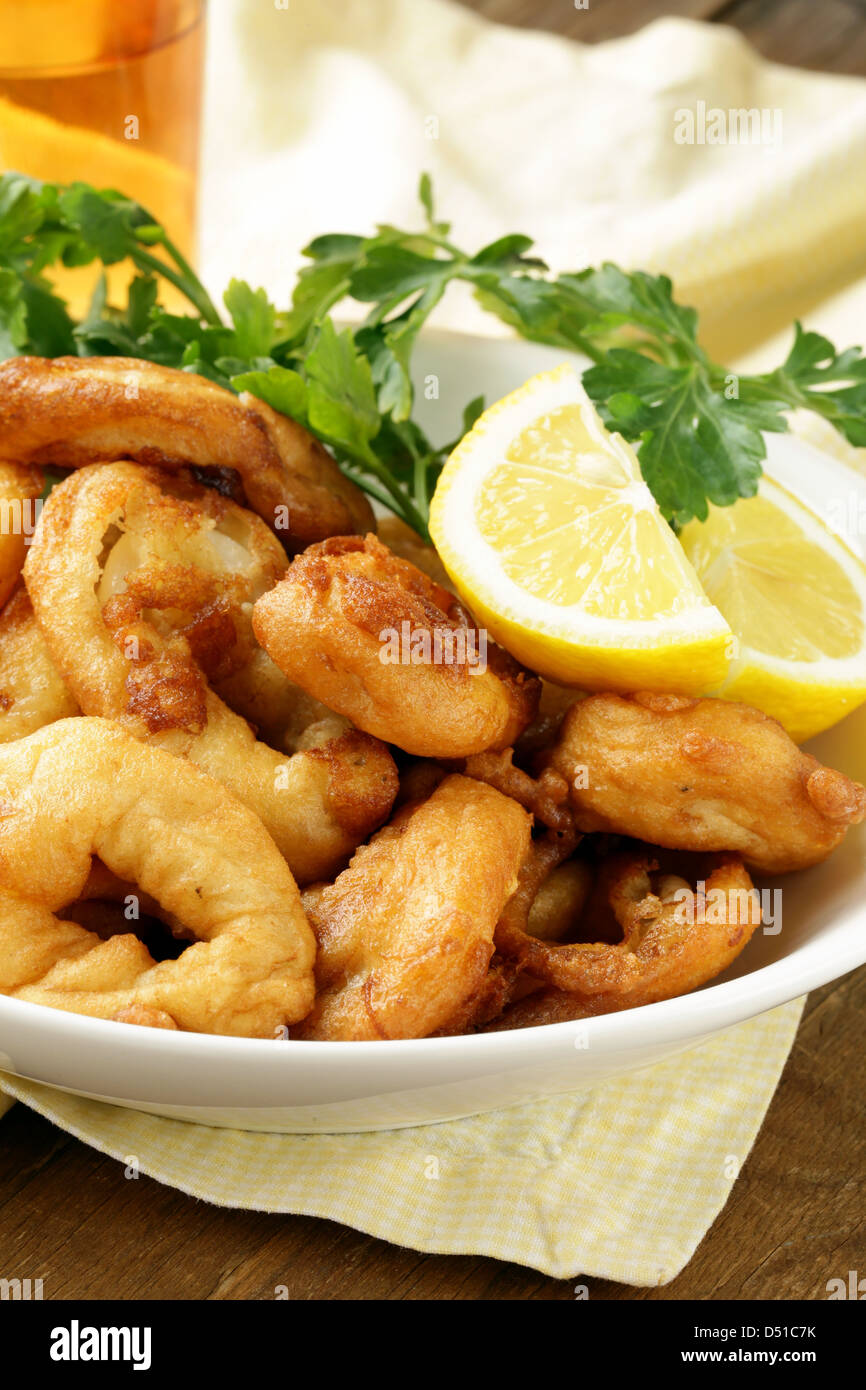 fried squid rings dipped in batter with lemon Stock Photo - Alamy