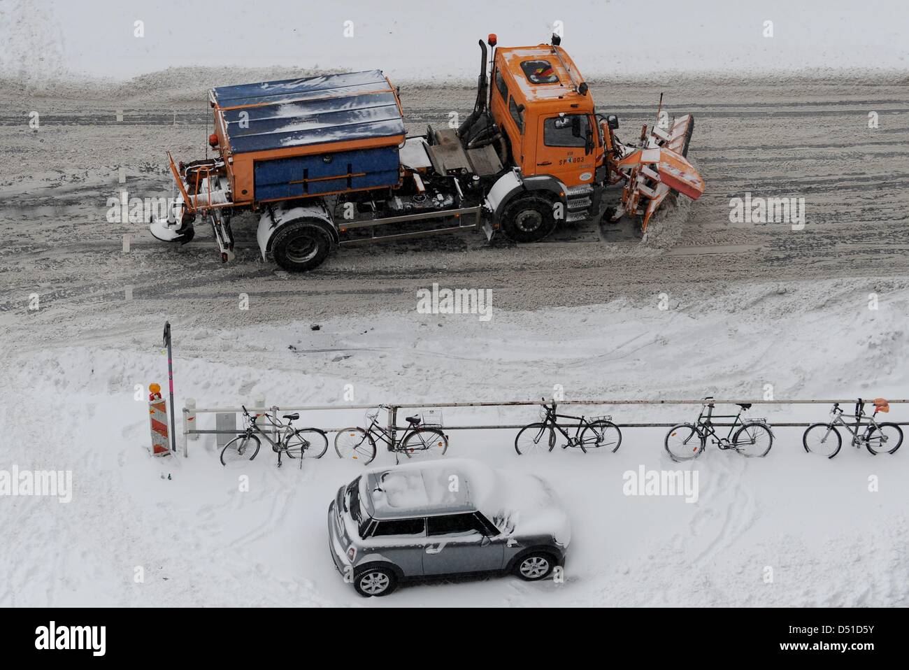 A snow-clearing vehicle drives along a snow-covered street in Berlin ...