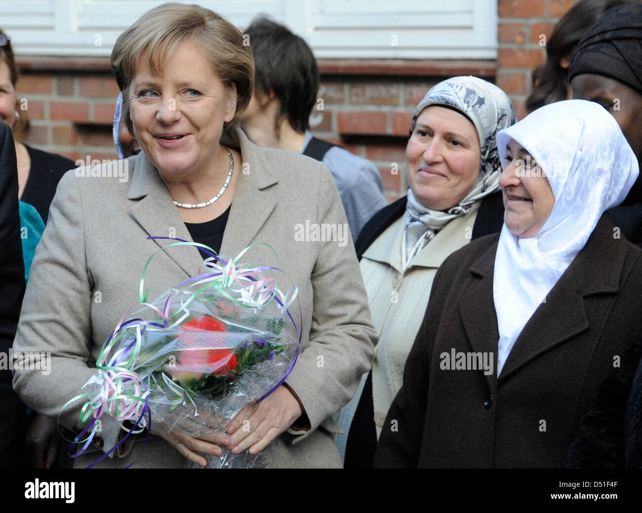 German Chancellor Angela Merkel (L) is greeted with flowers at the ...