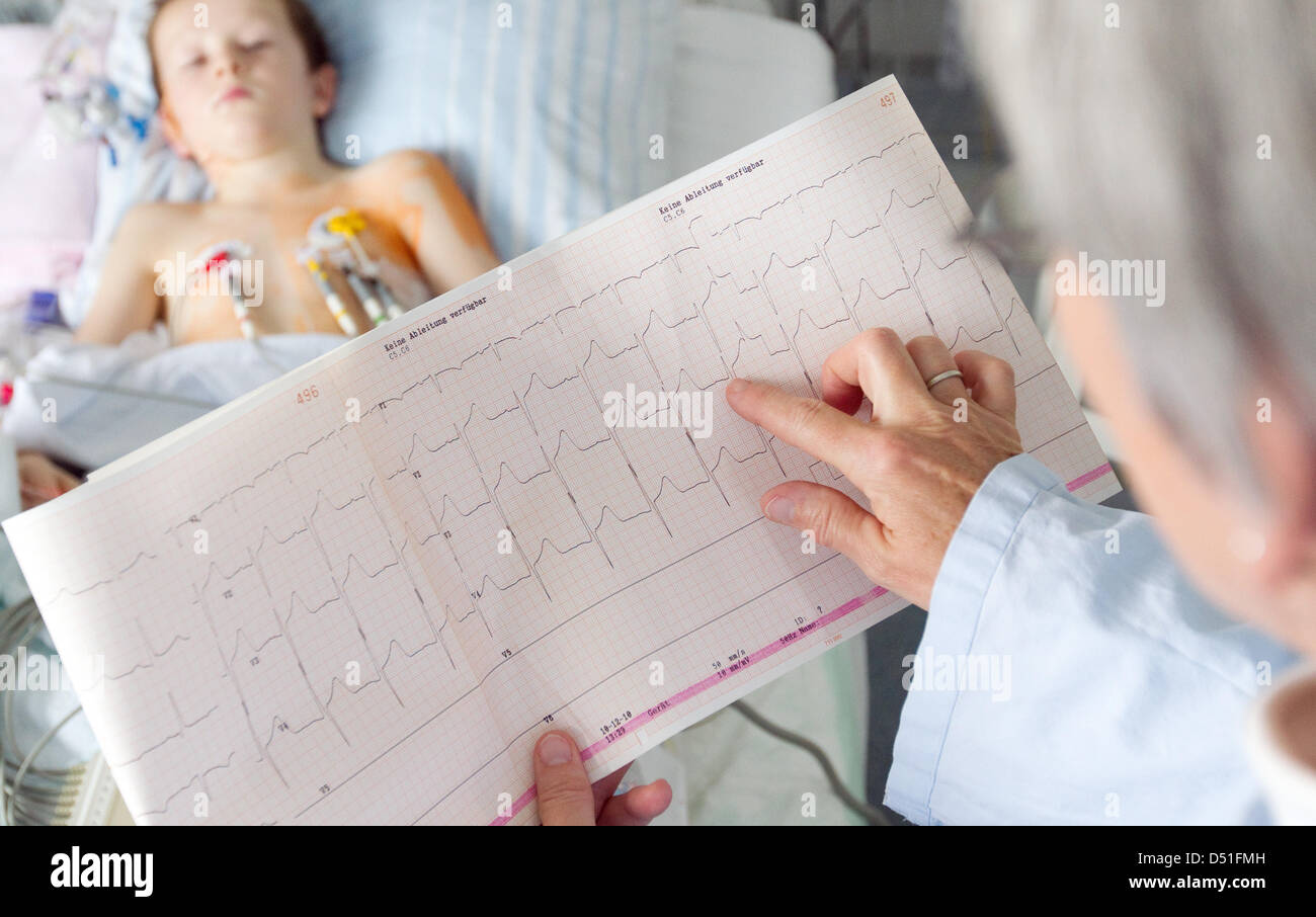 While a nurse reads his electrocardiogram (ECG), a child lies in an ...