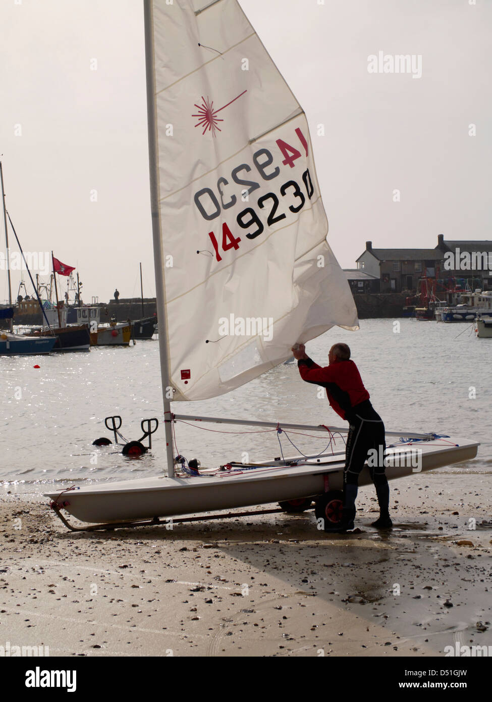 Sailing dinghy gathering sails at the slipway Stock Photo - Alamy