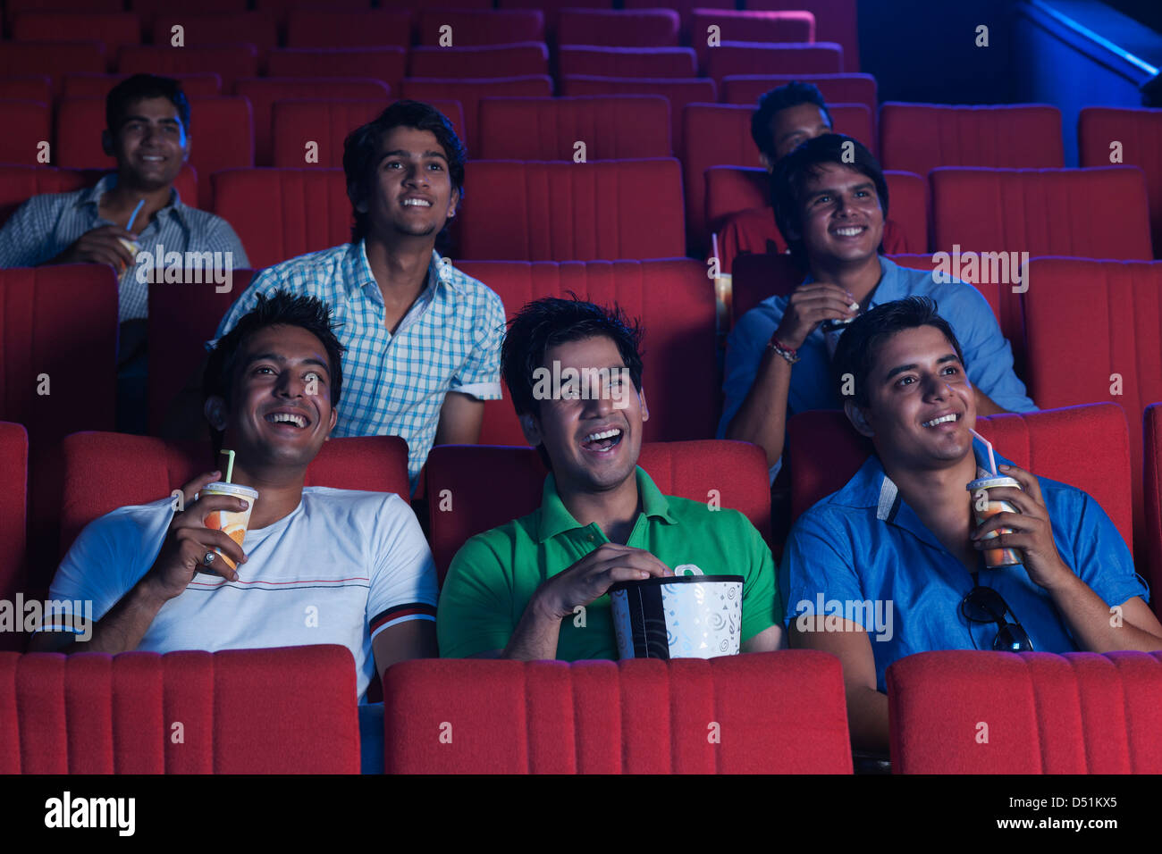 Youngsters enjoying movie with popcorns in a cinema hall Stock Photo ...