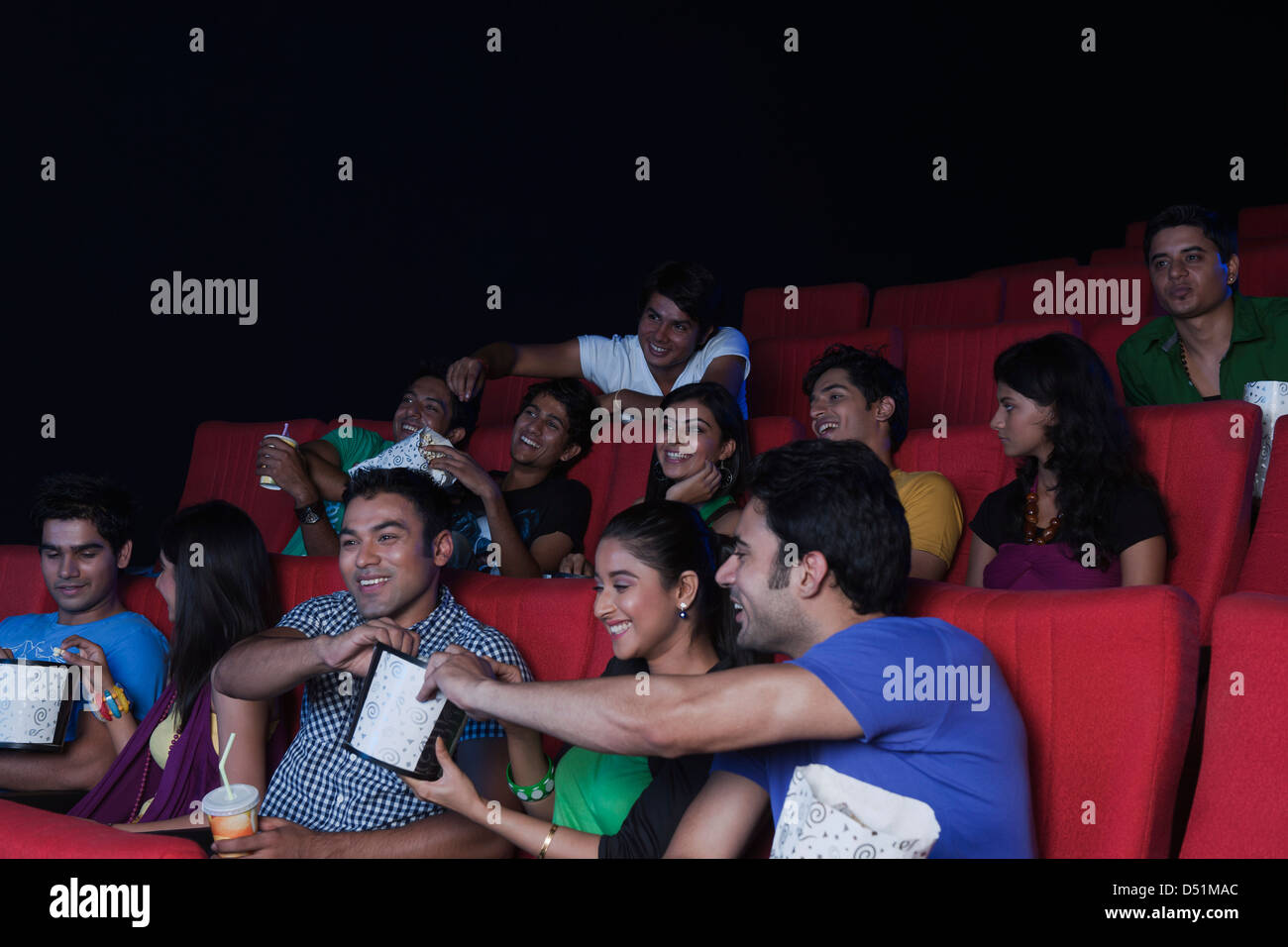 Youngsters enjoying movie in a cinema hall Stock Photo - Alamy