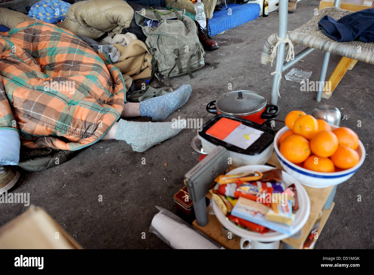 The feet of a homeless person peek out under a blanket at the ...