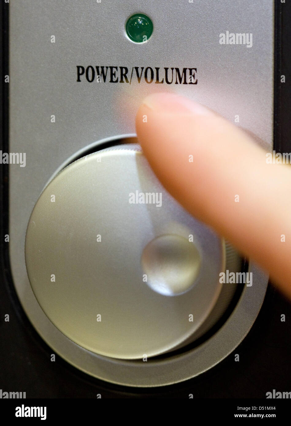 The illustration shows a finger turning the volume control wheel of a ...