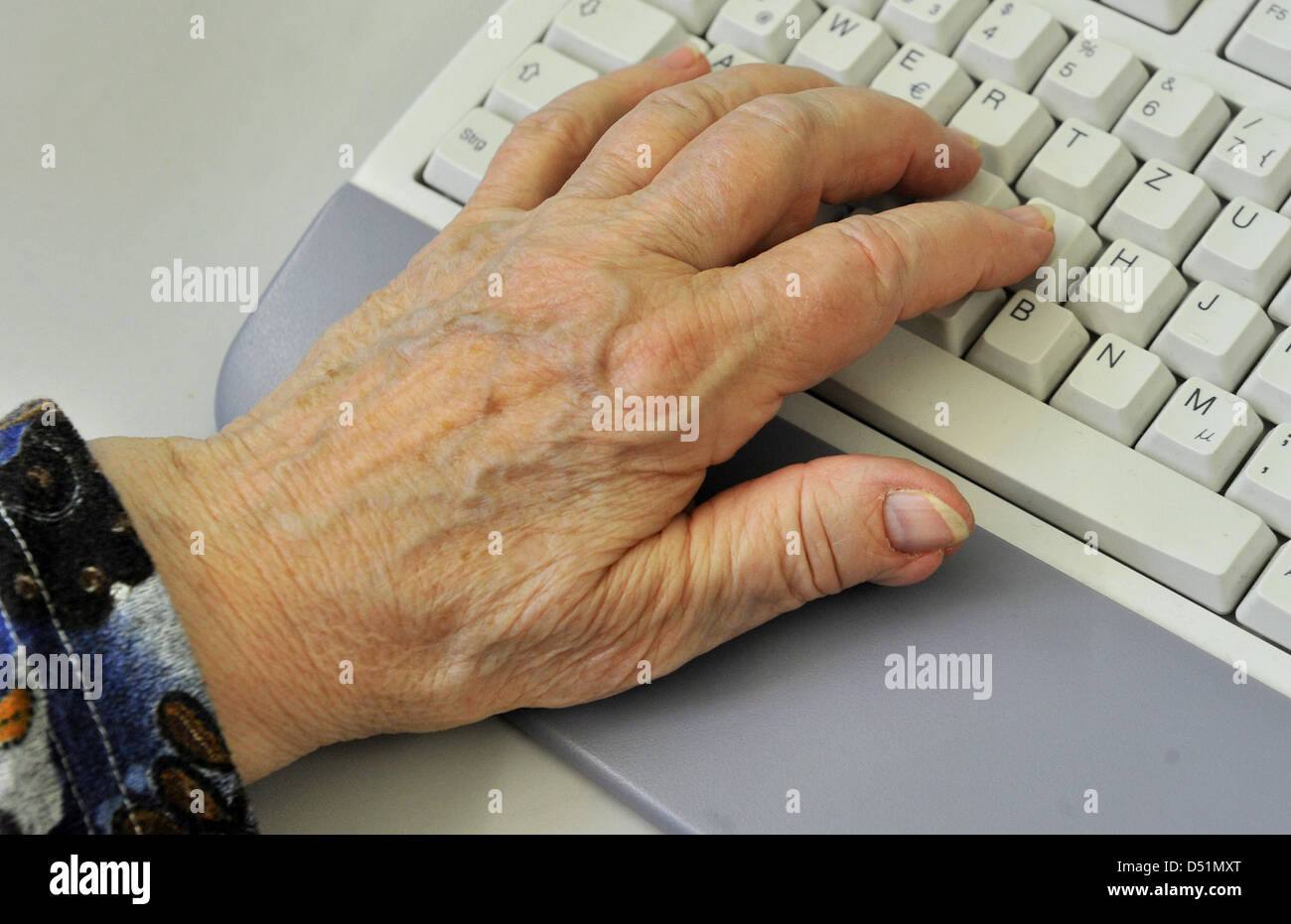 The hand of a senior citizen tips on a keyboard during an IT class for ...