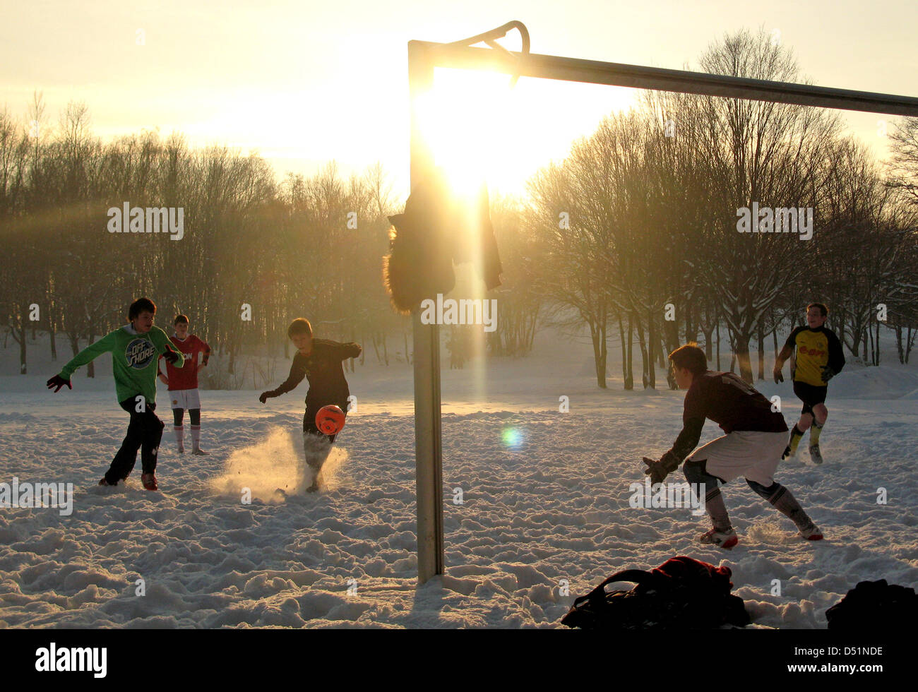 Youths play football on a snow covered football field in Dortmund ...