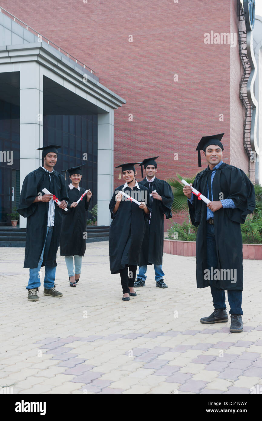 Portrait of graduate students holding diplomas and smiling in ...