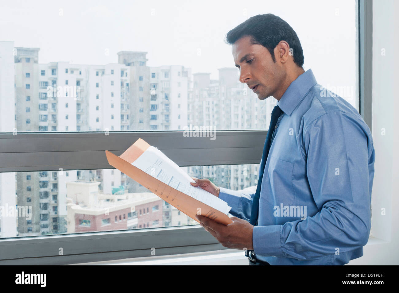 Businessman examining a file Stock Photo - Alamy