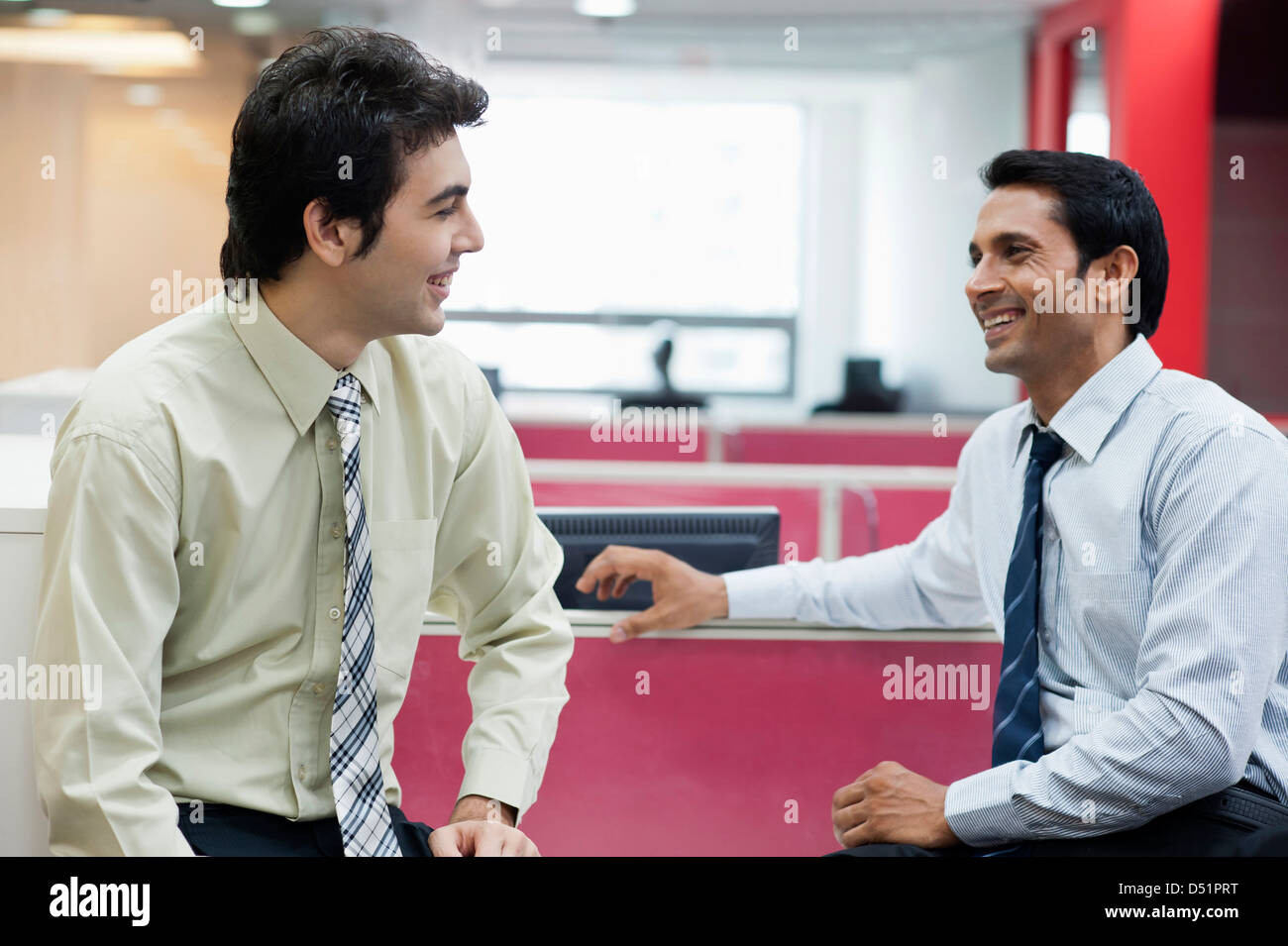 Two businessmen talking to each other and smiling Stock Photo - Alamy