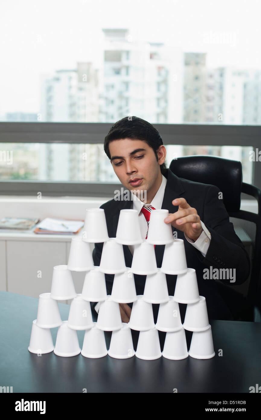 Businessman making a pyramid with disposable cups Stock Photo - Alamy
