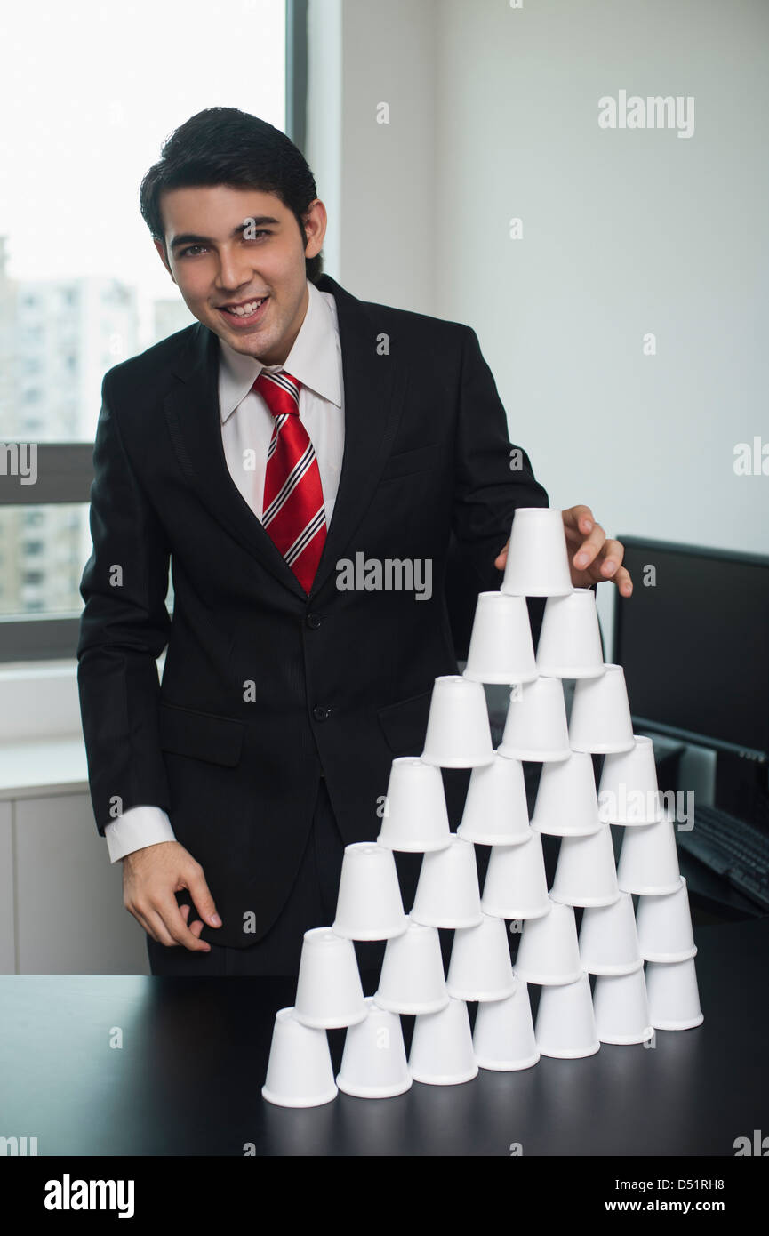 Businessman making a pyramid with disposable cups Stock Photo - Alamy
