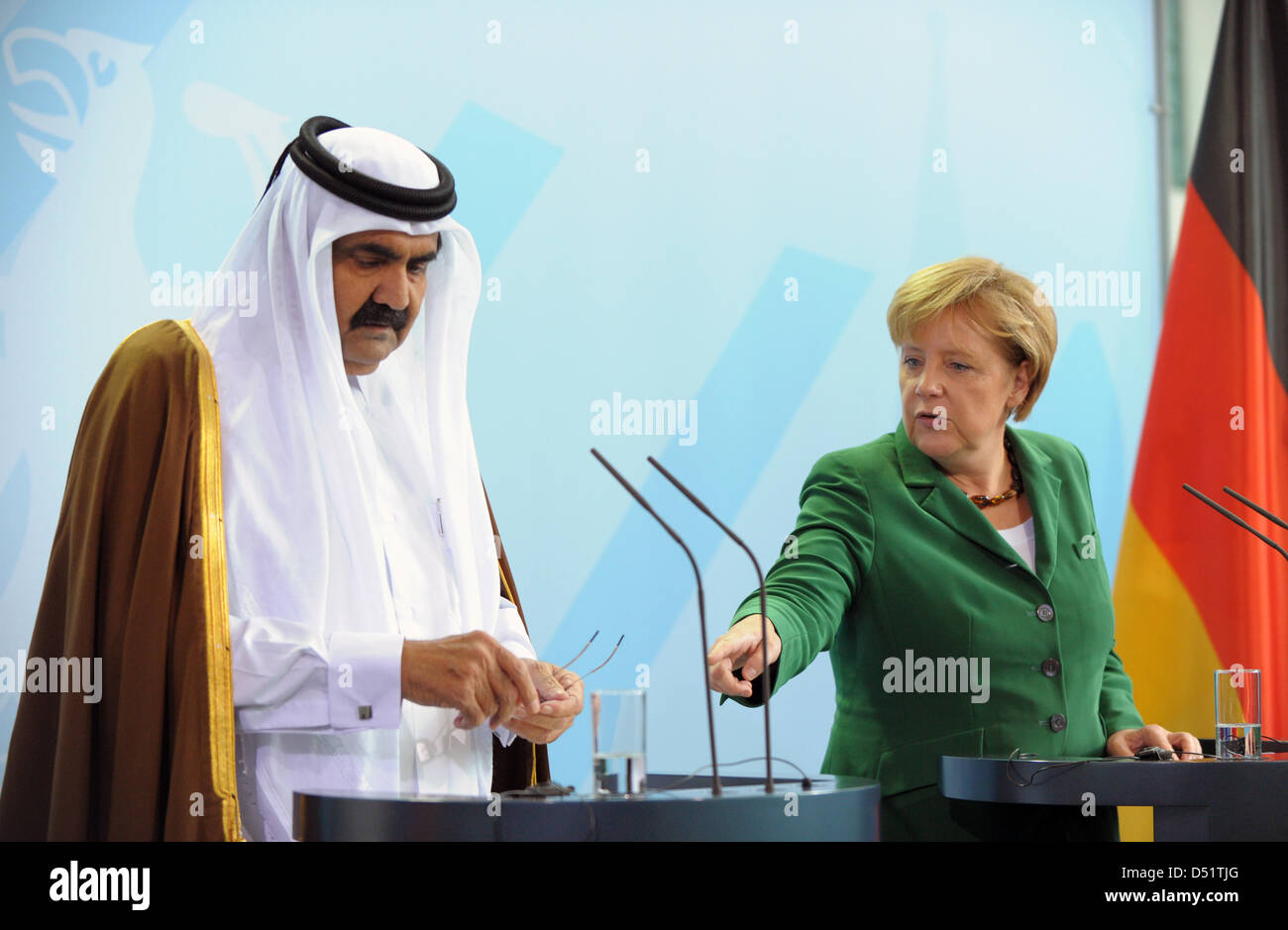 German Chancellor Angela Merkel (R) points to earphones lying on the ...