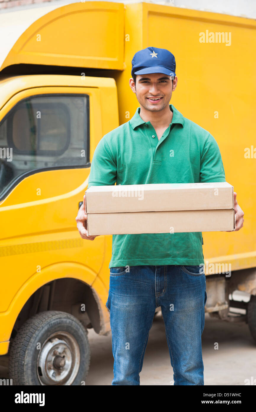 Delivery man holding cardboard boxes and smiling Stock Photo - Alamy