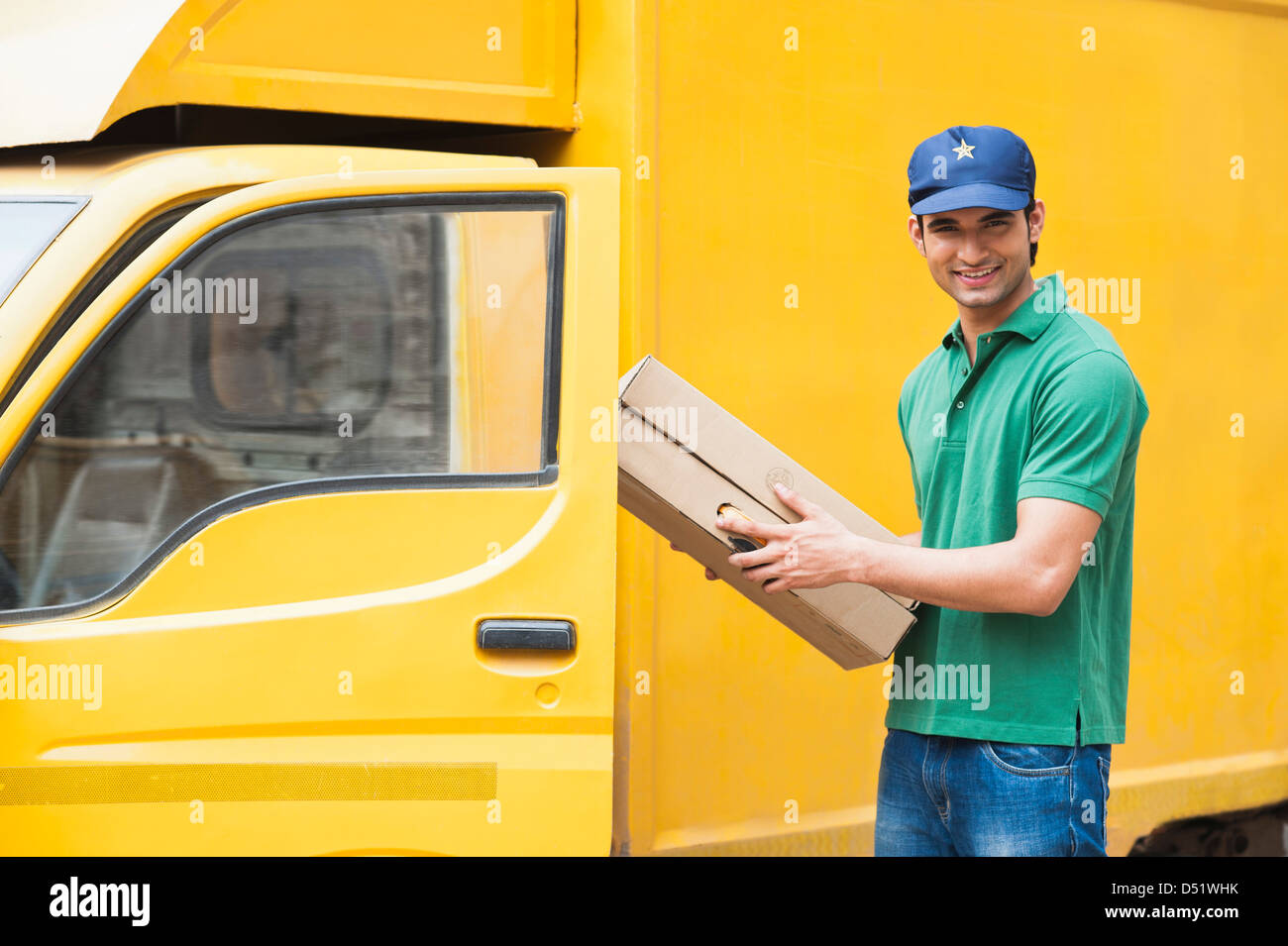 Delivery man holding cardboard boxes and smiling Stock Photo - Alamy