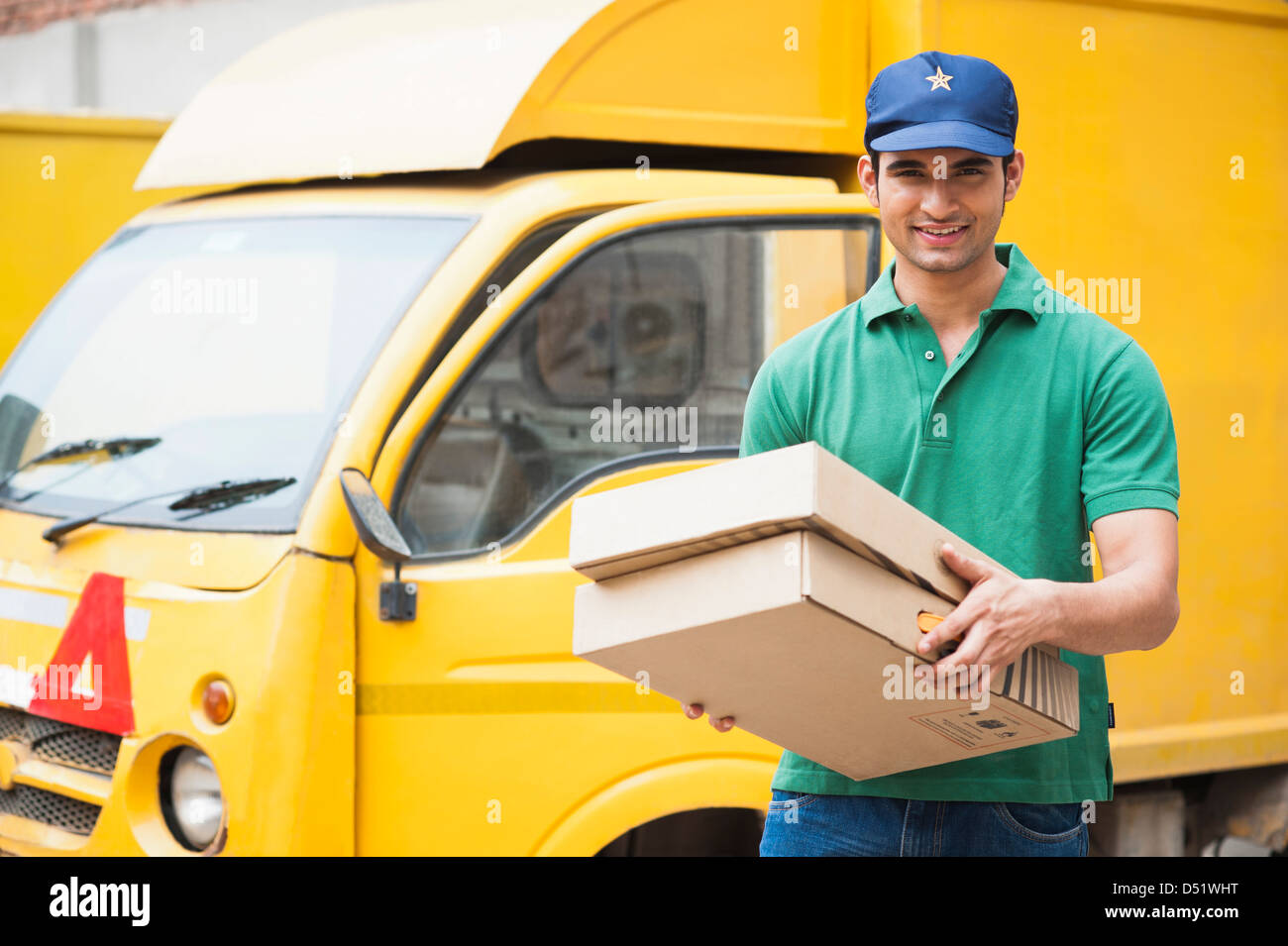 Delivery man holding cardboard boxes and smiling Stock Photo - Alamy