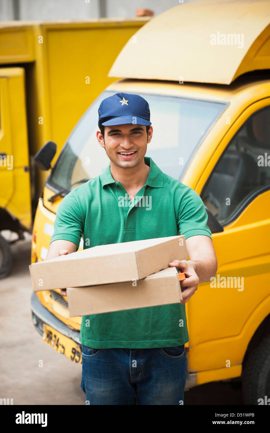 Delivery man holding cardboard boxes and smiling Stock Photo - Alamy