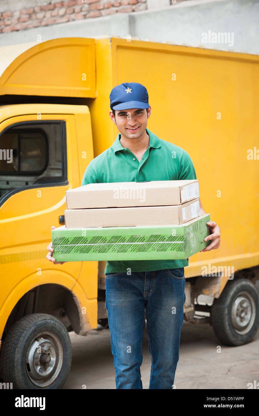 Delivery man holding cardboard boxes and smiling Stock Photo - Alamy