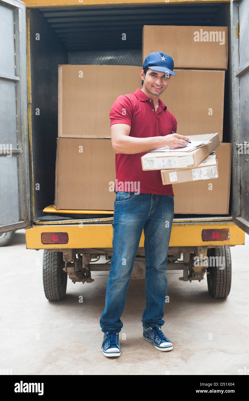 Delivery man holding cardboard boxes and smiling Stock Photo - Alamy