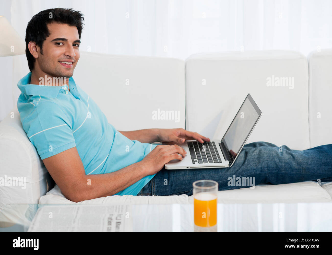 Man reclining on a couch and using a laptop Stock Photo - Alamy