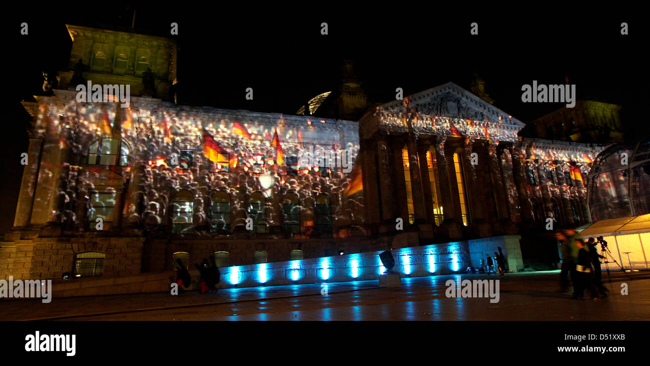 Reunification scenes are projected onto the Reichstag's facade on the ...