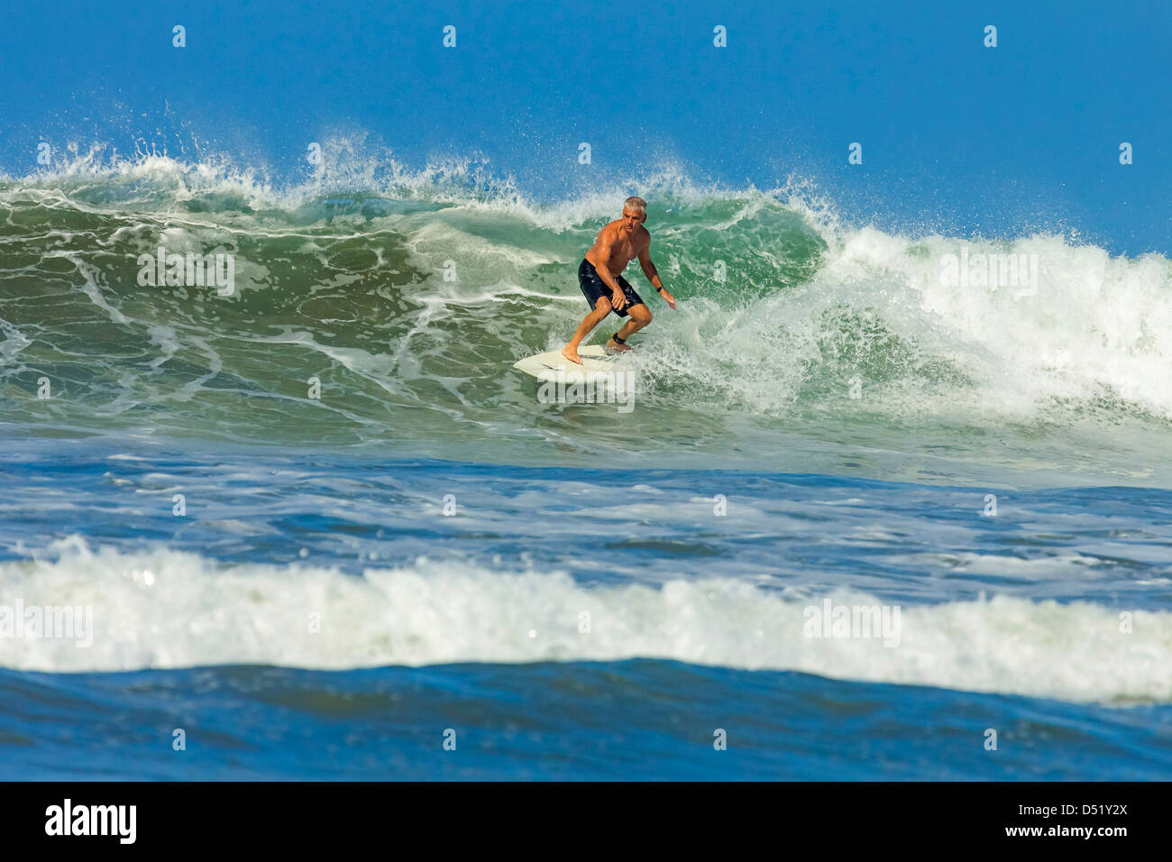 Surfer with grey hair surfing at popular Playa Guiones surf beach ...