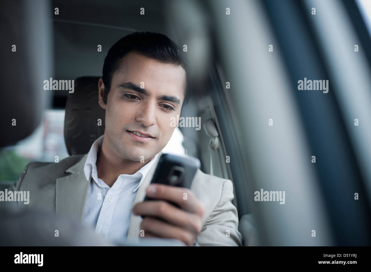 Businessman text messaging on a mobile phone in a car Stock Photo - Alamy