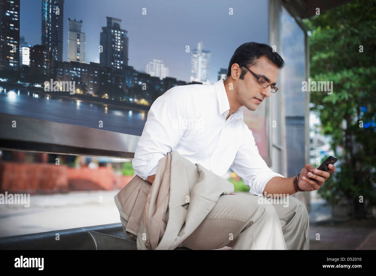 Businessman text messaging on a mobile phone at bus stop Stock Photo ...