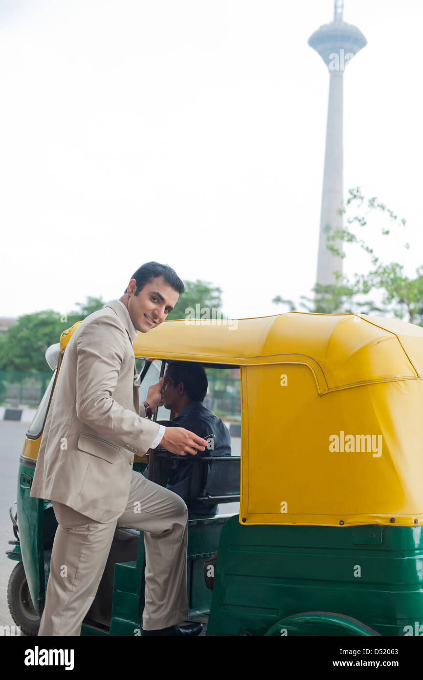 Portrait of a businessman getting into an auto rickshaw Stock Photo - Alamy