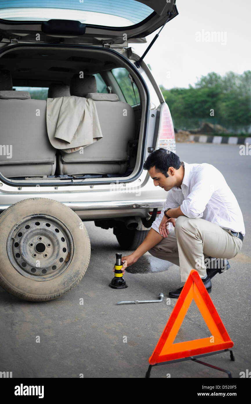 Businessman changing a car tire at roadside Stock Photo - Alamy