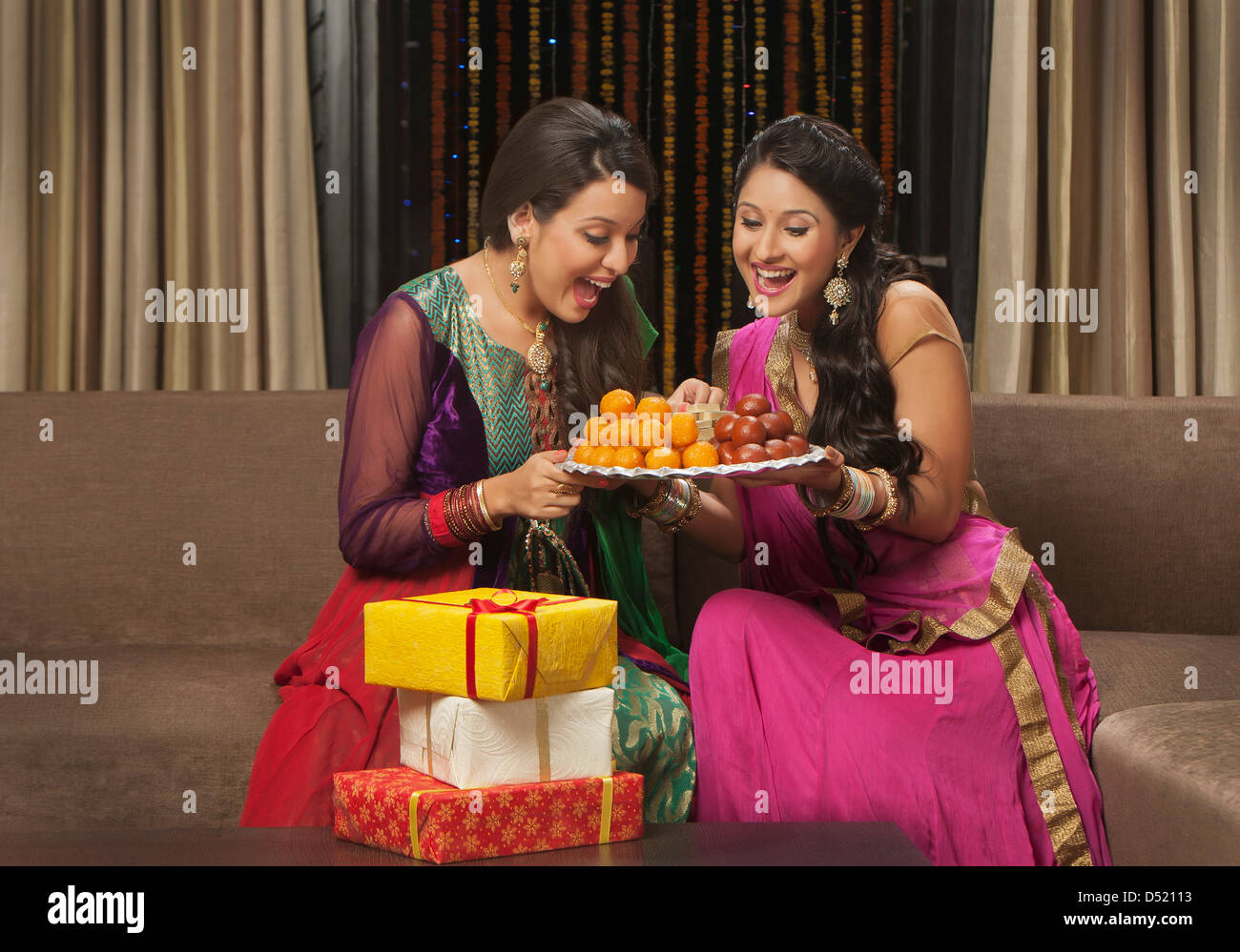 Female friends eating sweets on Diwali Stock Photo - Alamy