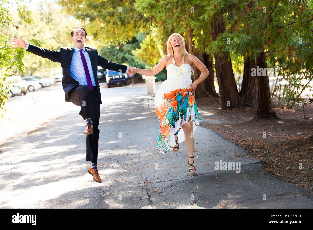 Caucasian newlywed couple skipping on road Stock Photo - Alamy
