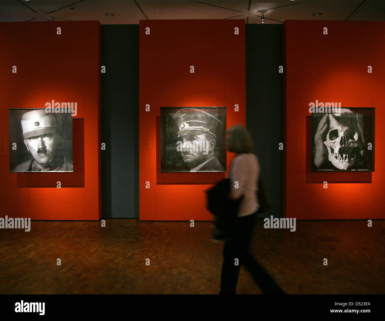 A woman passes by photos of Hitler that are projected onto a wall ...