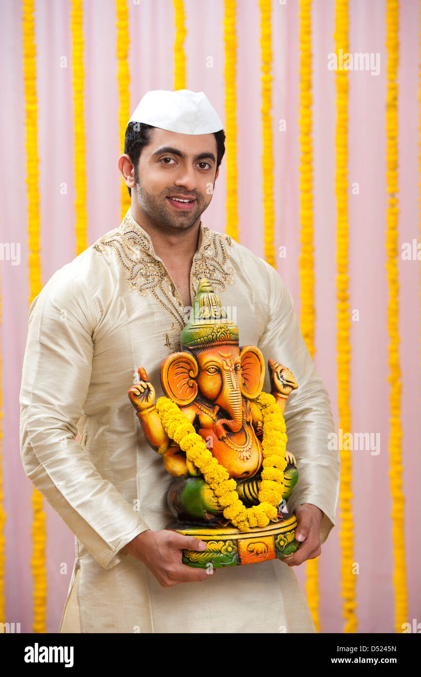 Maharashtrian man holding an Idol of Lord Ganesha during Ganesh ...