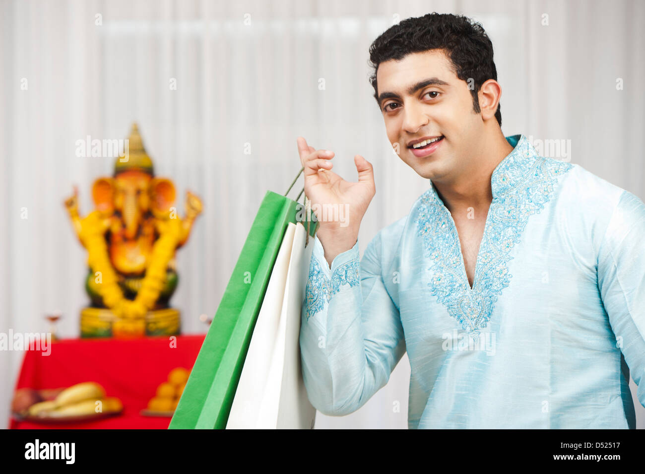 Maharashtrian man holding shopping bags and smiling during ganesh ...
