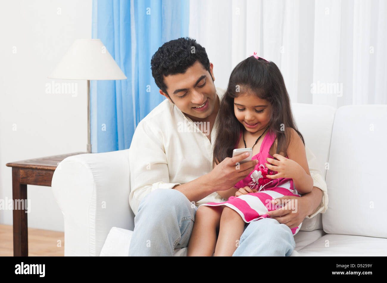Man using a mobile phone with his daughter Stock Photo - Alamy