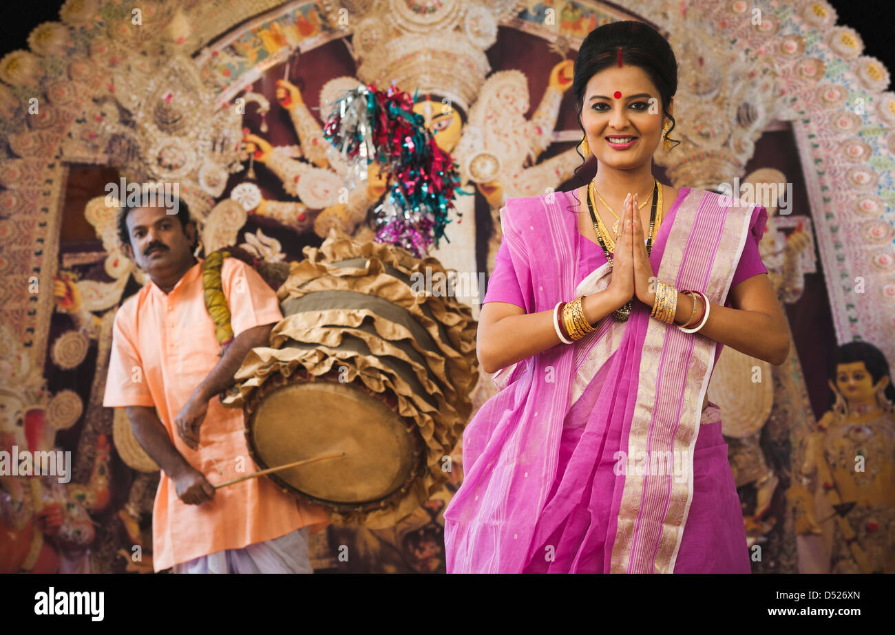 Bengali woman standing in a prayer position and a Dhaki playing Dhak at ...