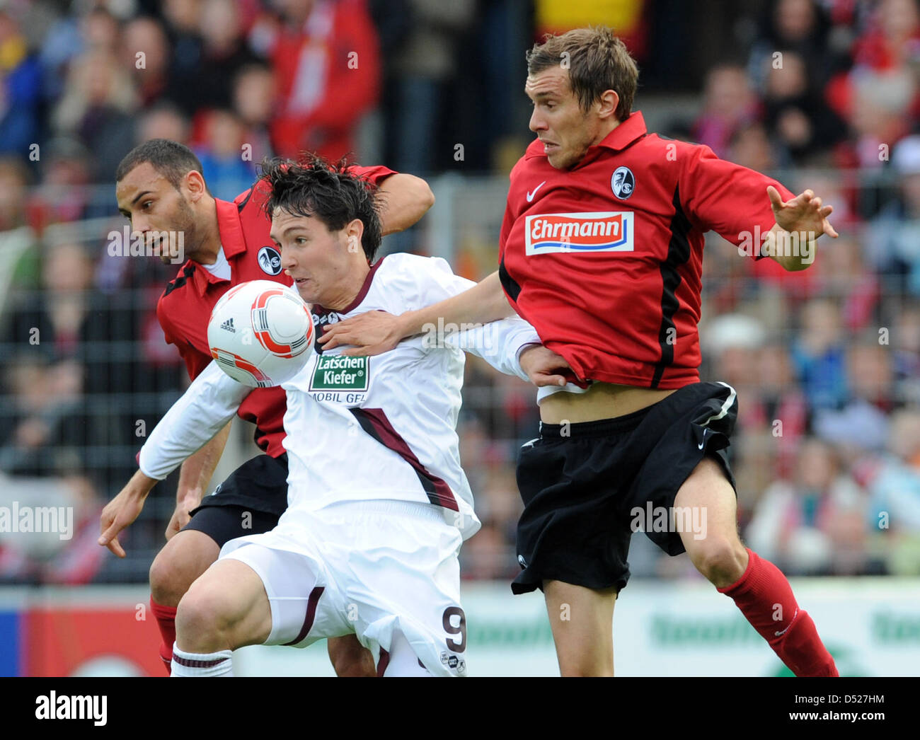 Freiburg's Oemer Toprak and Julian Schister (R) vie for the ball with ...
