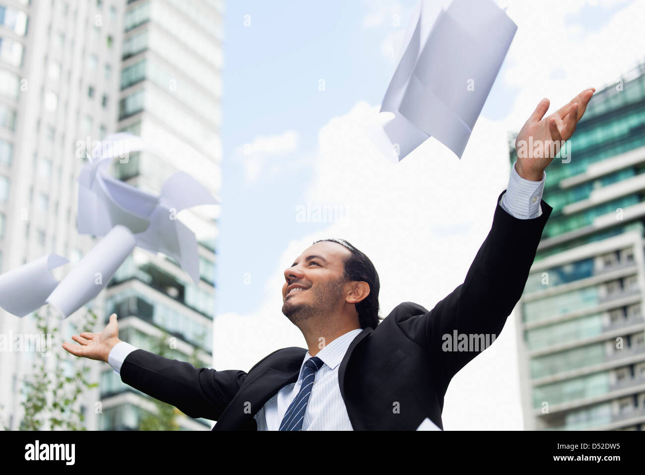 Businessman throwing paper in air, smiling Stock Photo - Alamy