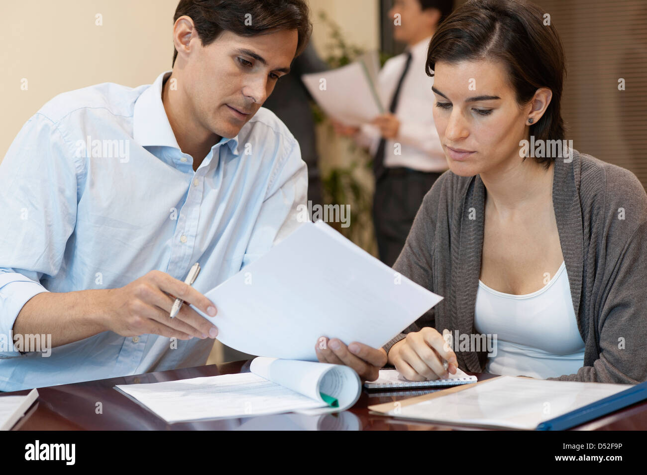Colleagues discussing document in office Stock Photo - Alamy
