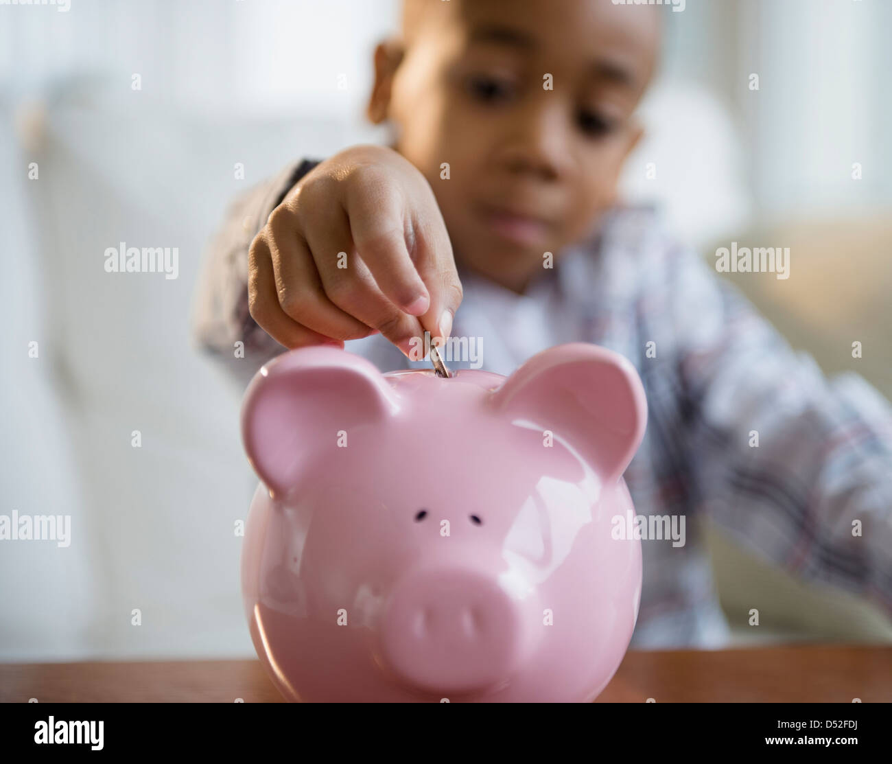 Boy putting coin in piggy hi-res stock photography and images - Alamy