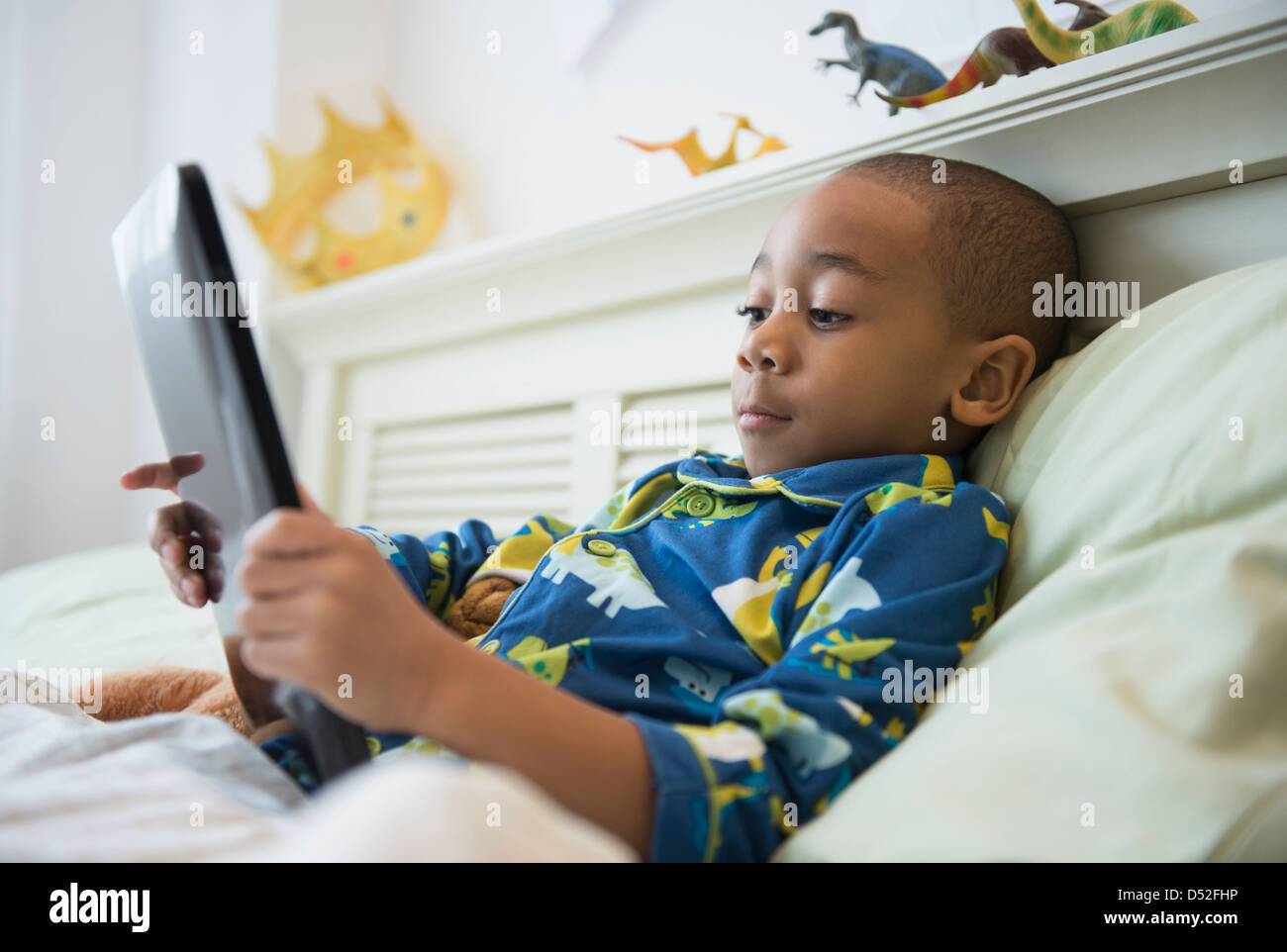 African American boy using tablet computer in bed Stock Photo - Alamy