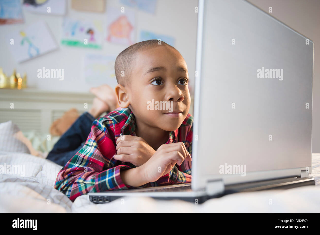 African American boy using laptop on bed Stock Photo - Alamy