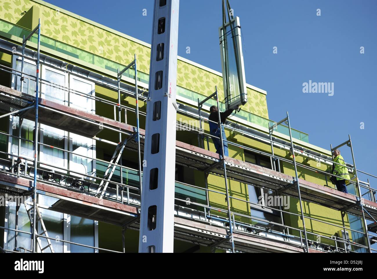 Workers attach glass elements to the facade of the so-called 'BIQ House ...