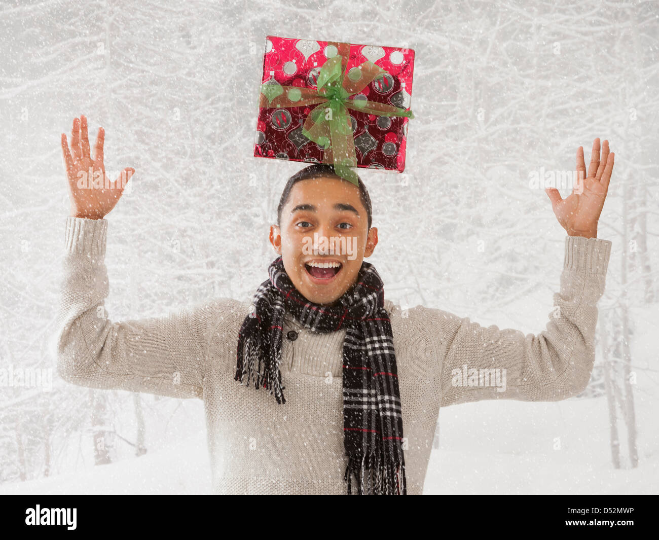 Hispanic man balancing present on head in snow Stock Photo - Alamy
